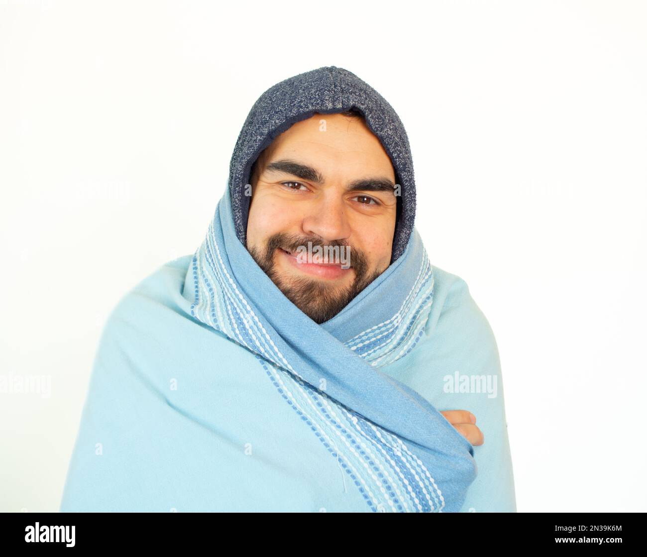 Young bearded man wearing winter clothes covering with a blue blanket ...