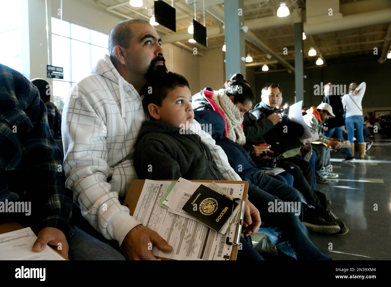 Miguel Ayala waits with his son Jesus with other immigrants to register ...