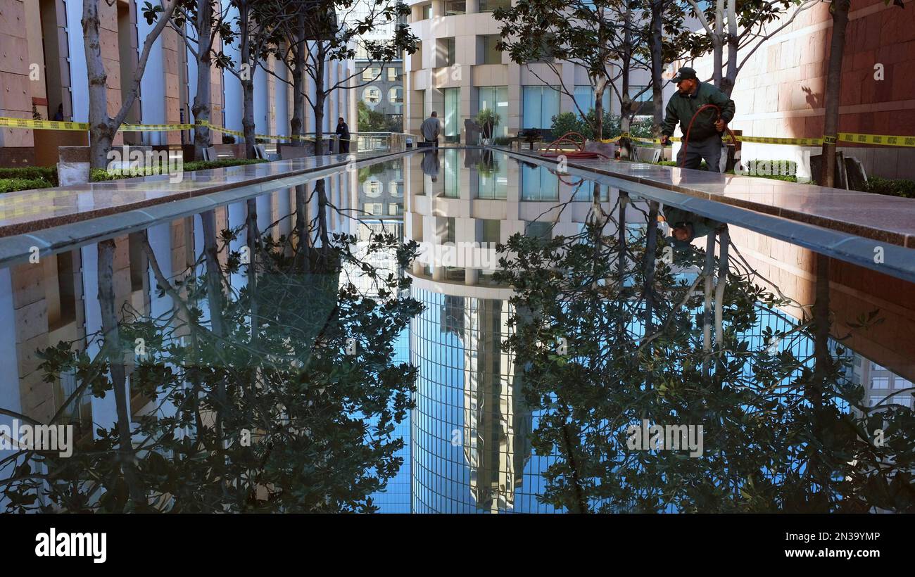 Landscape workers water trees surrounding an office building in ...
