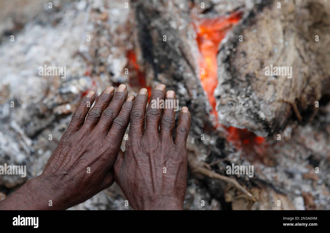An Indian villager warms himself near a bonfire on a cold morning in ...