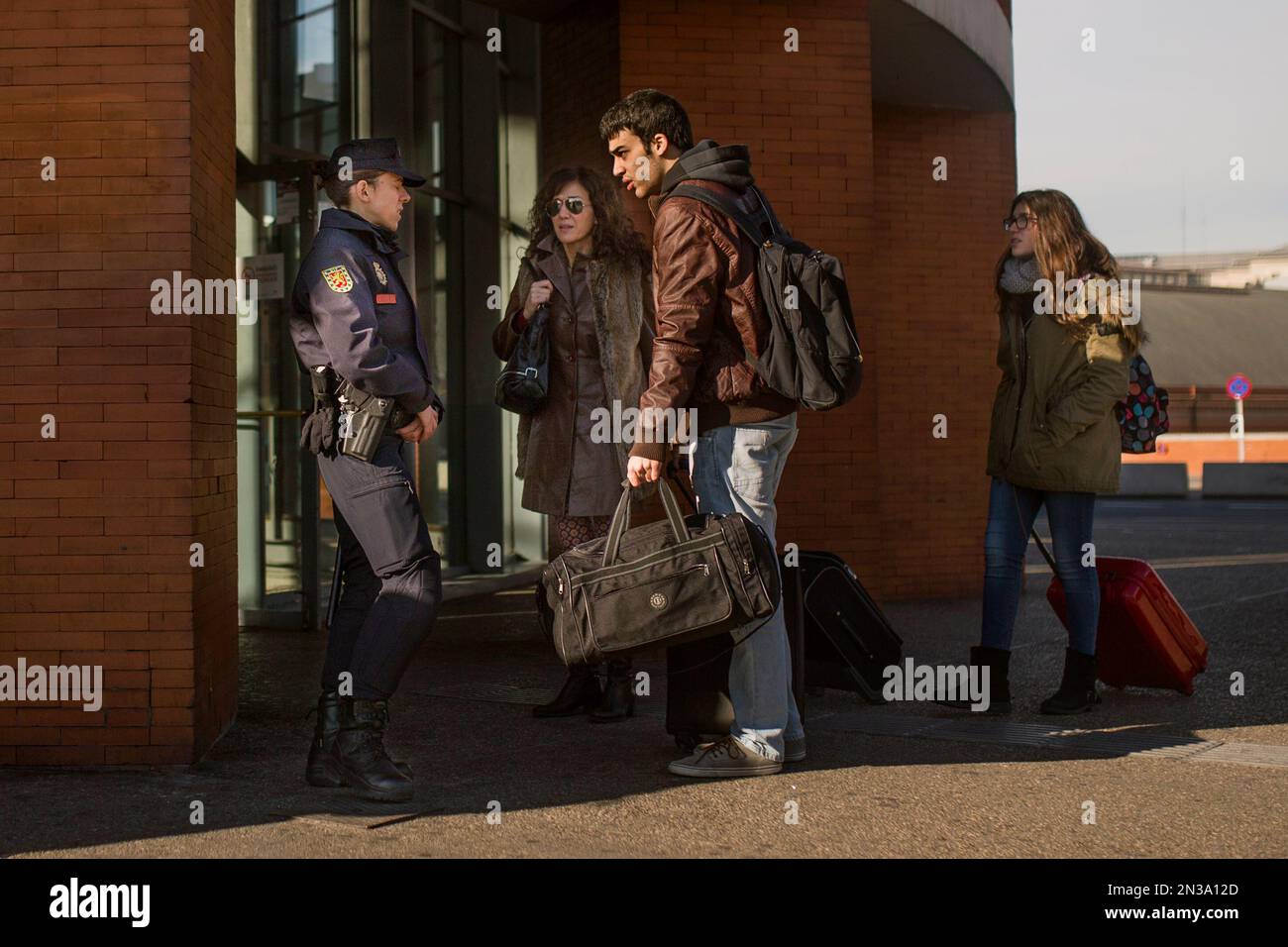 Passengers talk to the police as she stands guard outside Atocha train ...