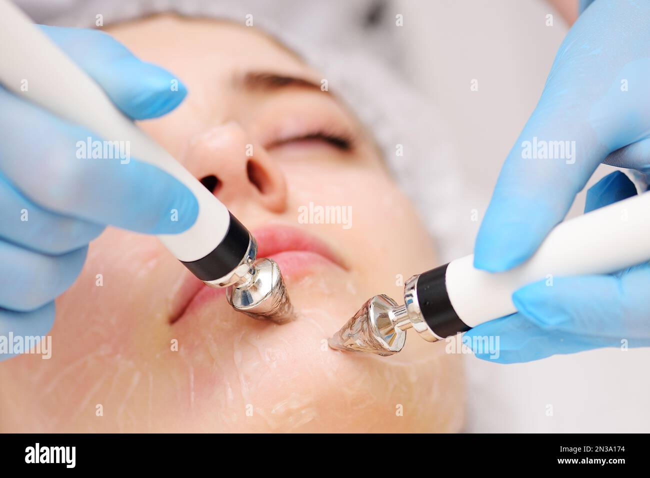cosmetologist conducts microcurrent facial therapy for a young woman ...