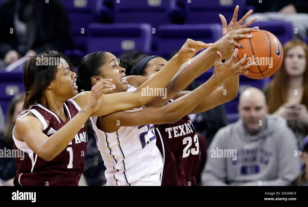 Washington's Aminah Williams, center, reaches for a loose ball between ...