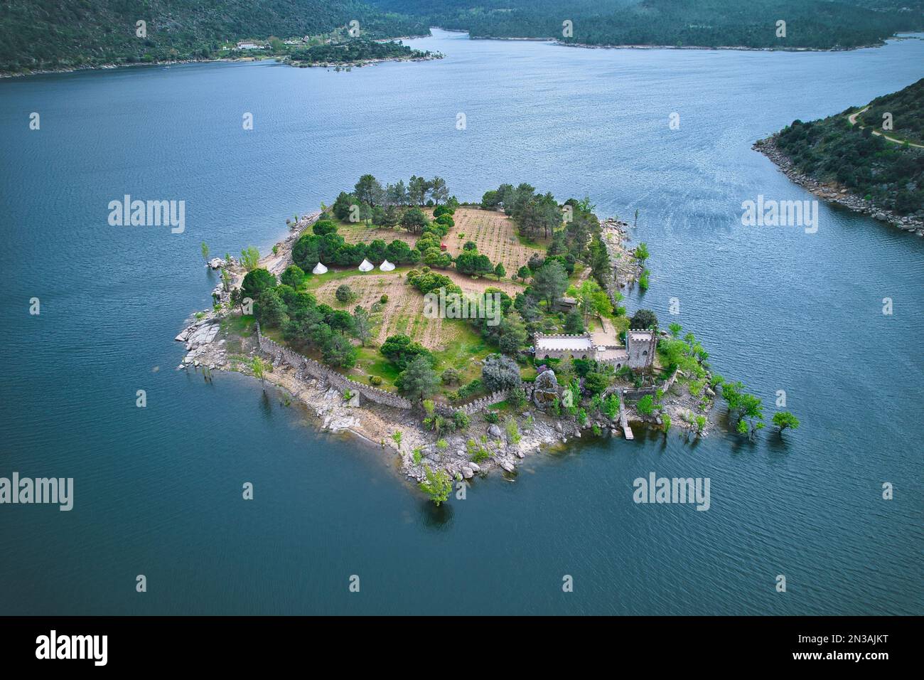 An aerial shot of a small island with vegetation and a castle ...