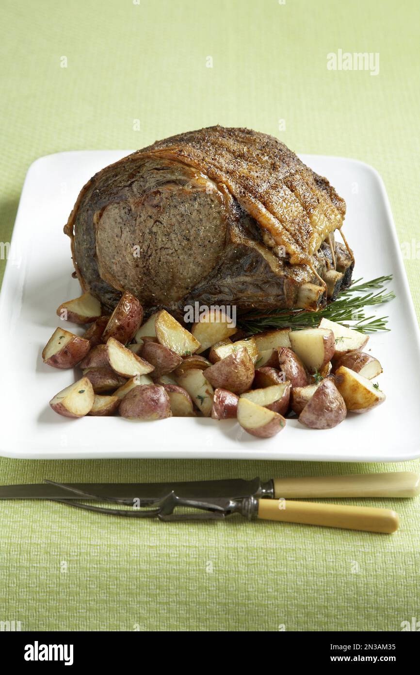 Prime rib roast beef with baby red potatoes on a green background Stock ...