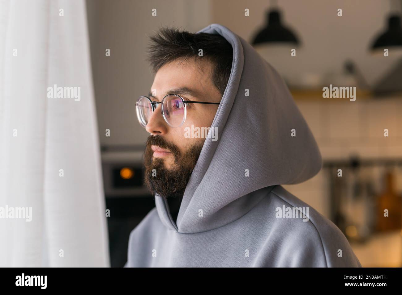 Side view of man longing and looking through window in sad day ...