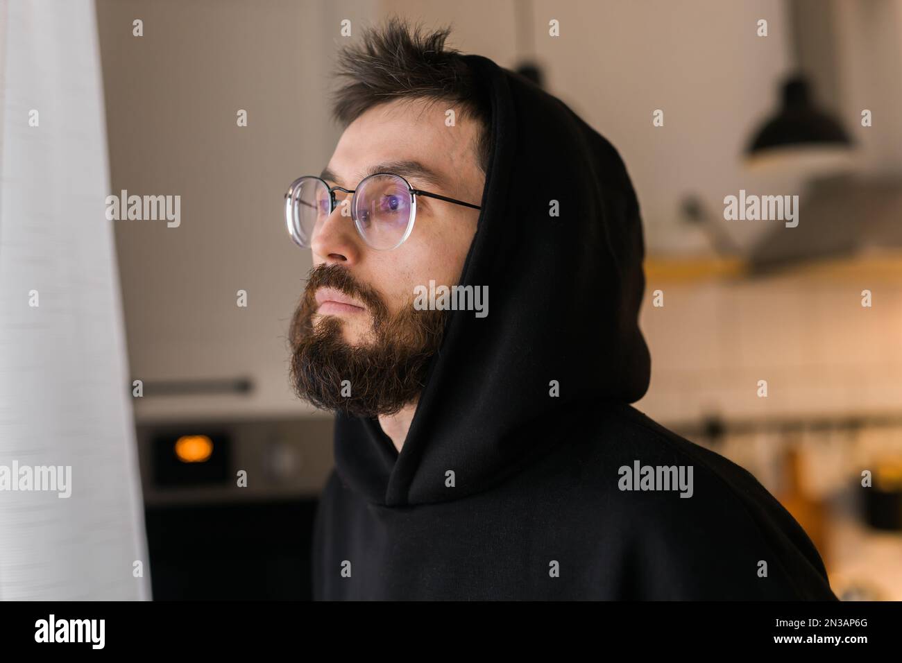 Side view of man longing and looking through window in sad day ...