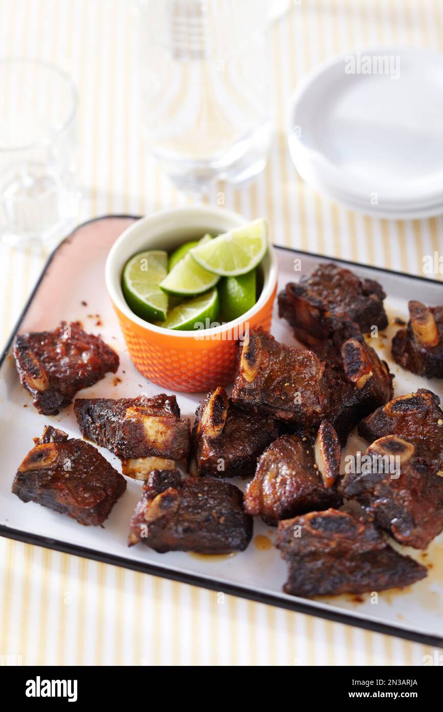 Beef Ribs with spice rub, served with lime wedges on a platter Stock ...