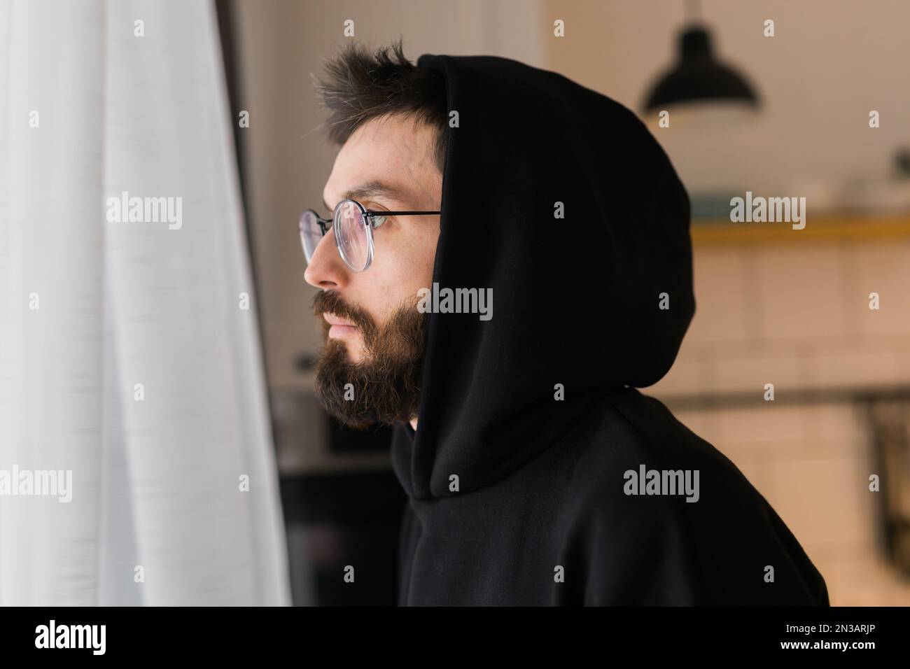Side view of man longing and looking through window in sad day ...