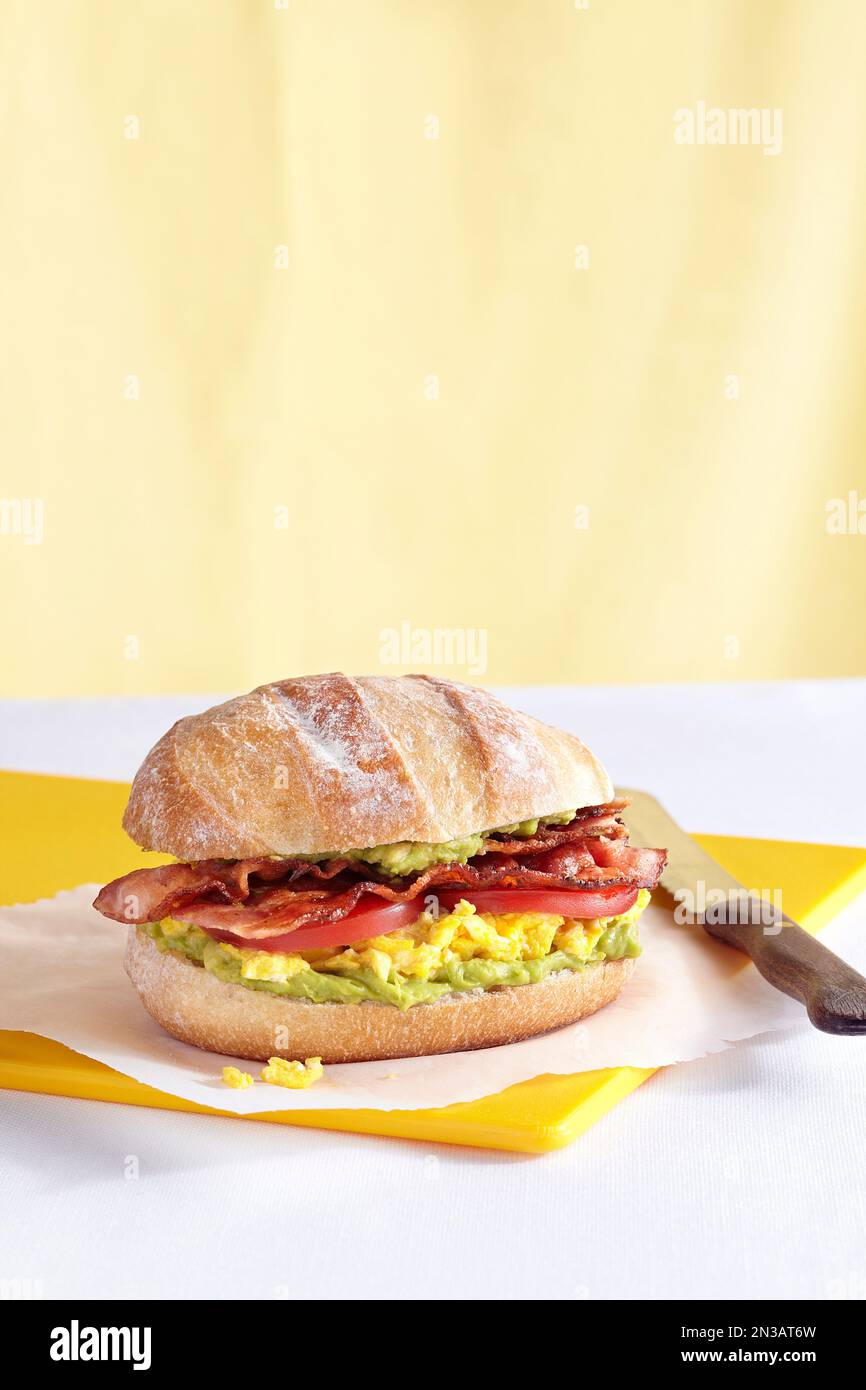 Breakfast Sandwich, with bacon, tomato, egg and mashed avocado on a bun ...