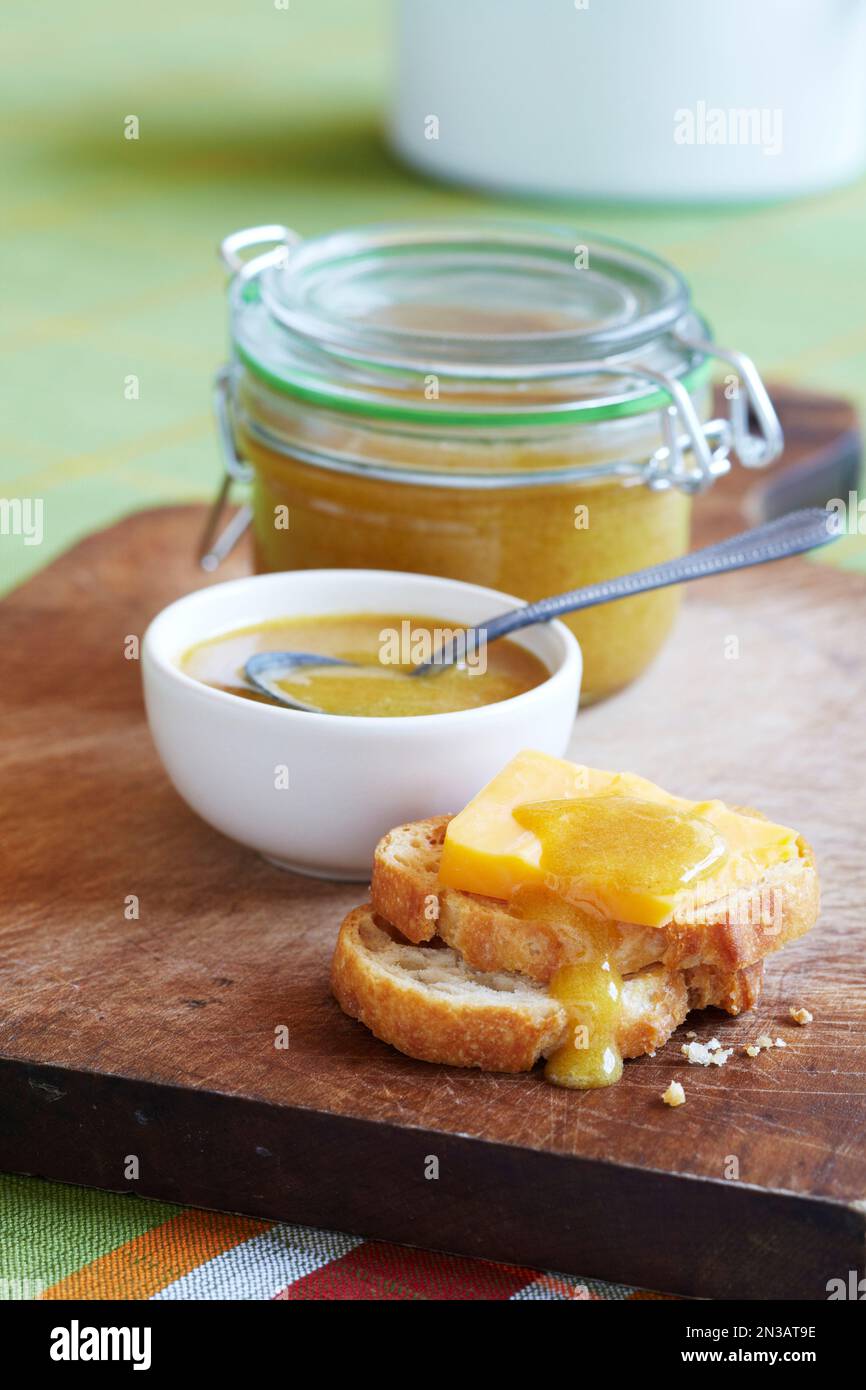 Honey mustard on bread with chesse on wooden cutting board with jar and ...