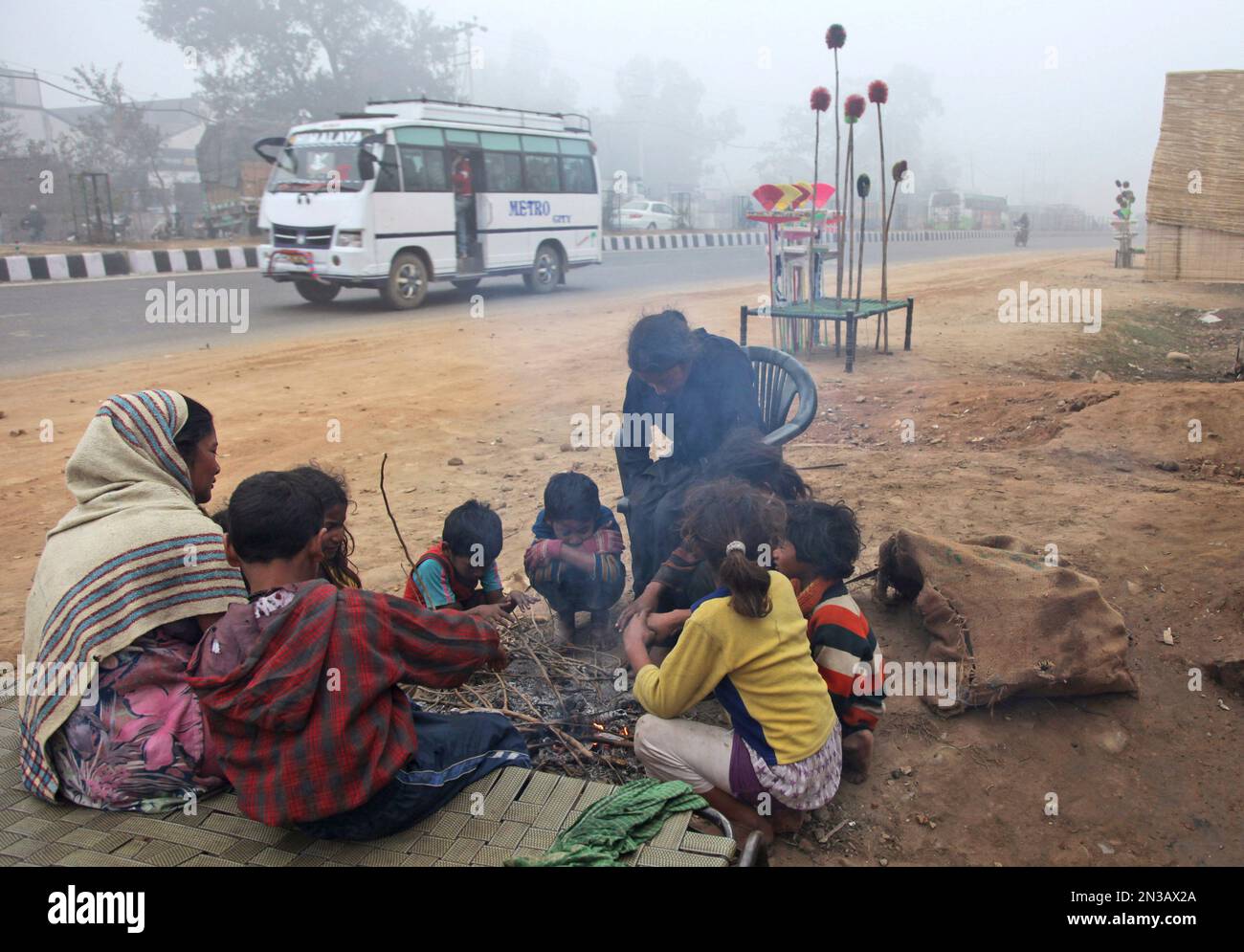 Indian homeless people keep themselves warm while sitting around a ...