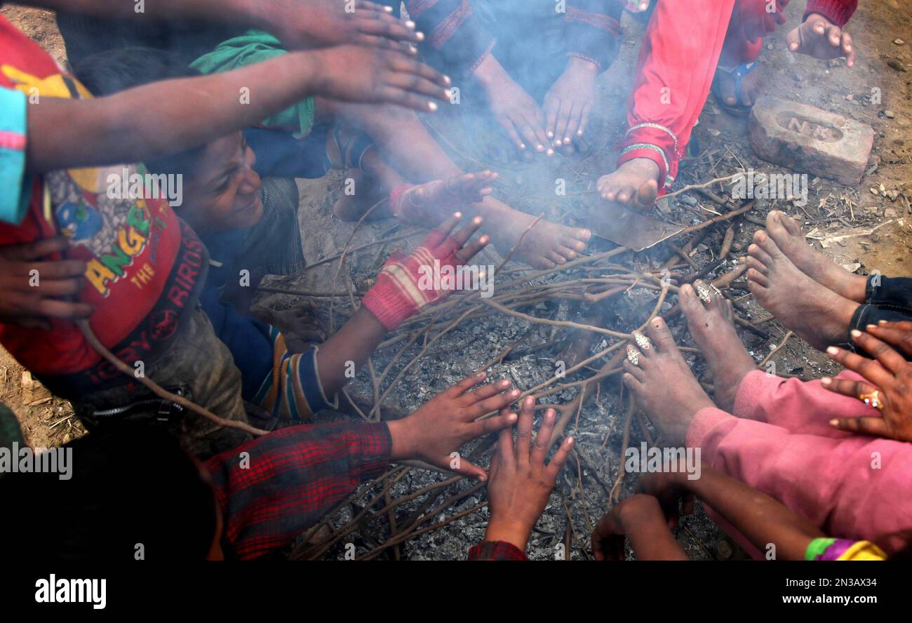 Indian homeless people keep themselves warm while sitting around a ...