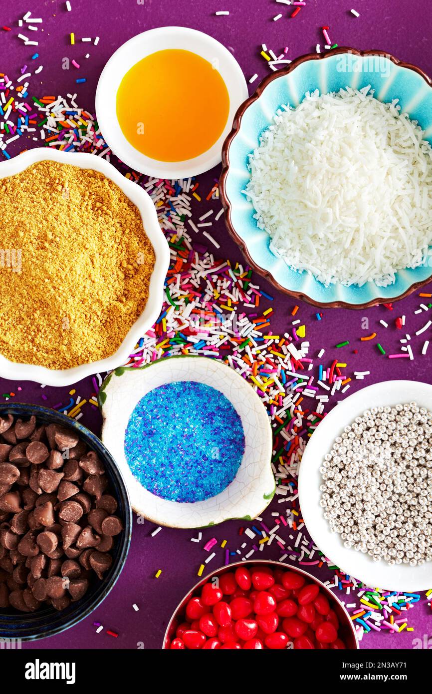 Sprinkles, chocolate chips and other cupcake toppings on a purple ...