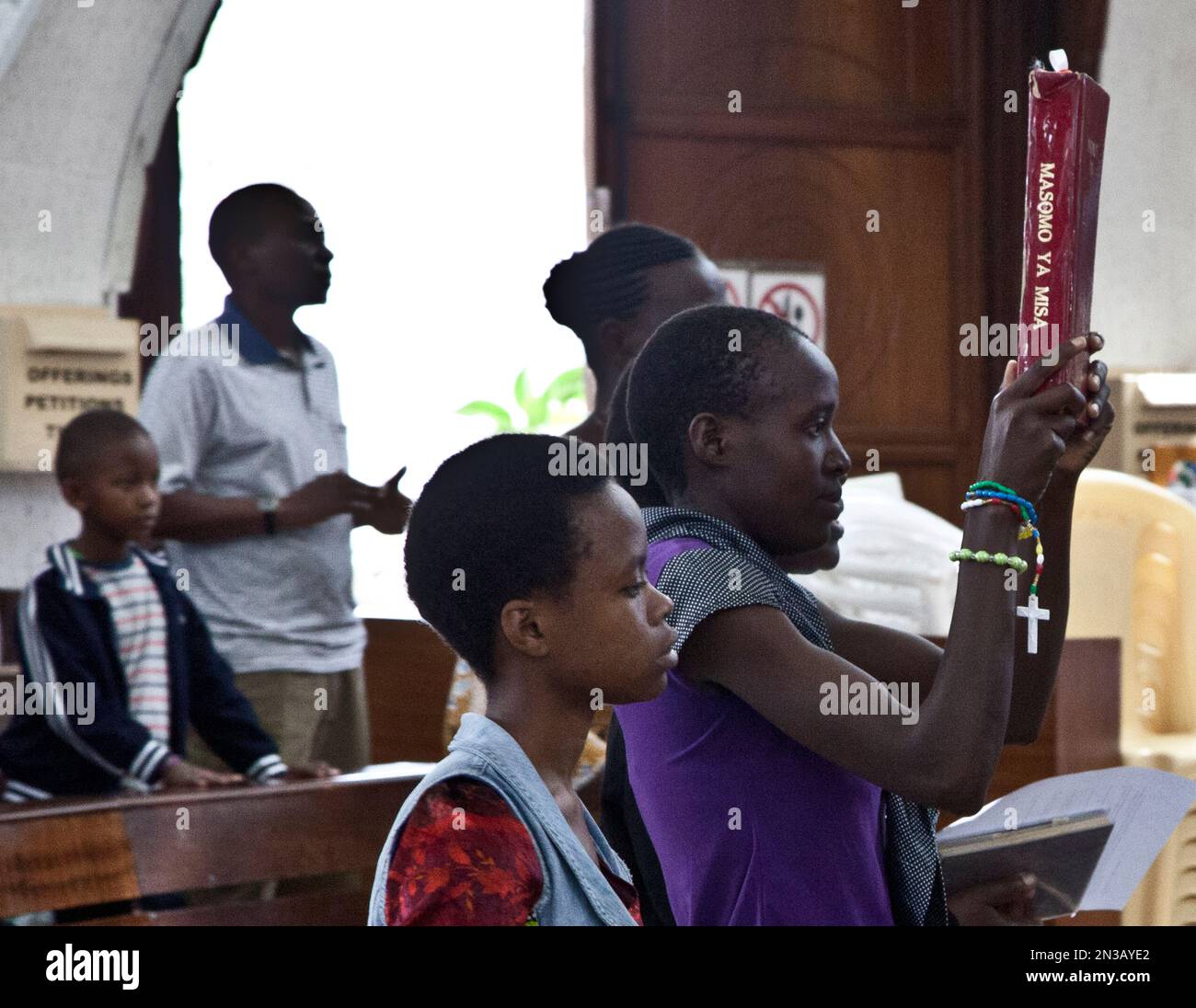 A Kenyan Christian holds the Bible in Kiswahili as she joins others for ...