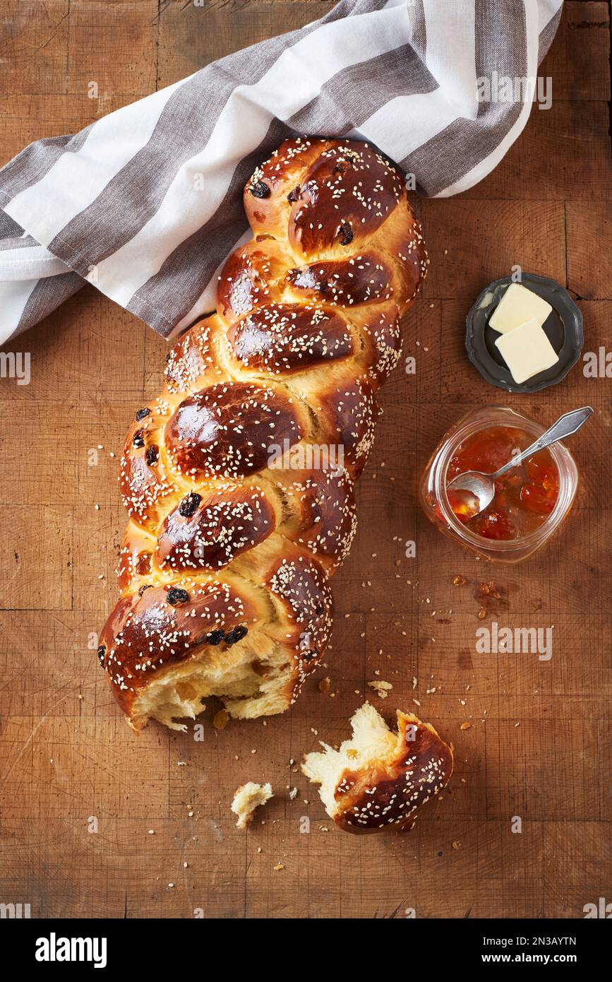 Challah bread with raisins served with butter and jam on butcher block ...