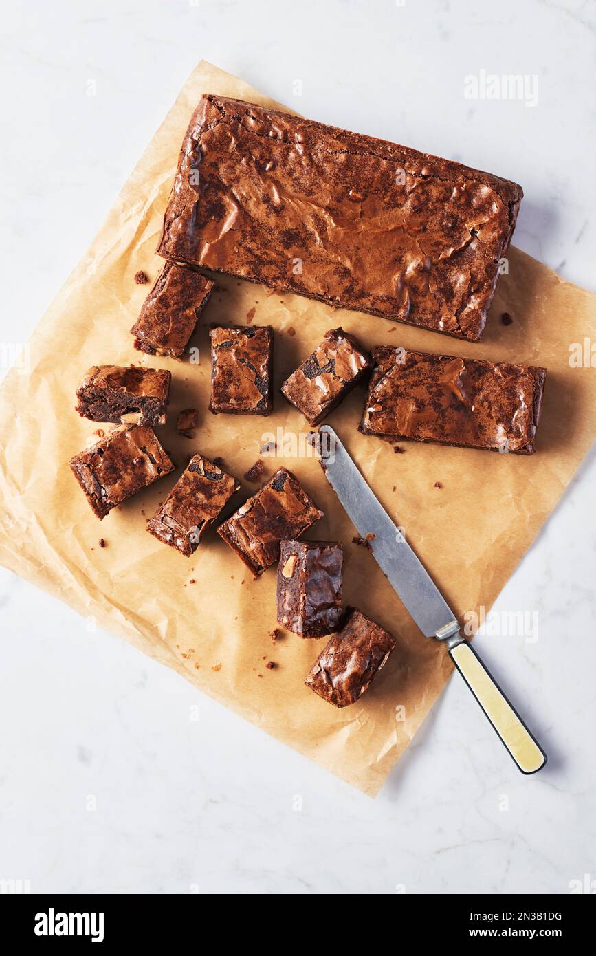 Brownies with toffee chunks cut into pieces on parchment paper with a ...