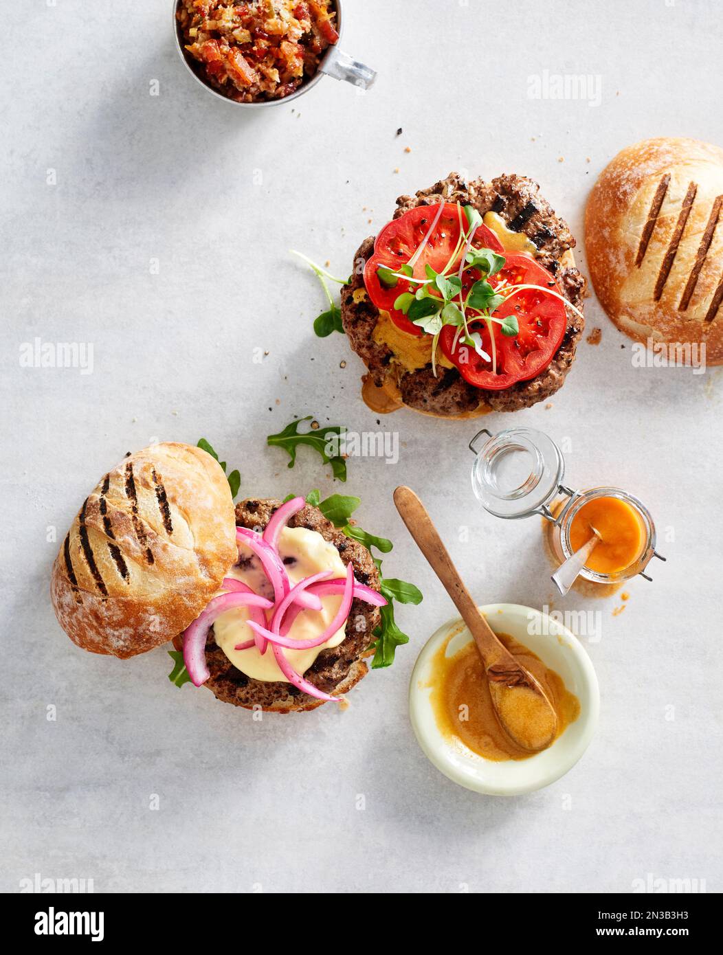 Burgers with a variety of condiments on a light stone surface Stock ...