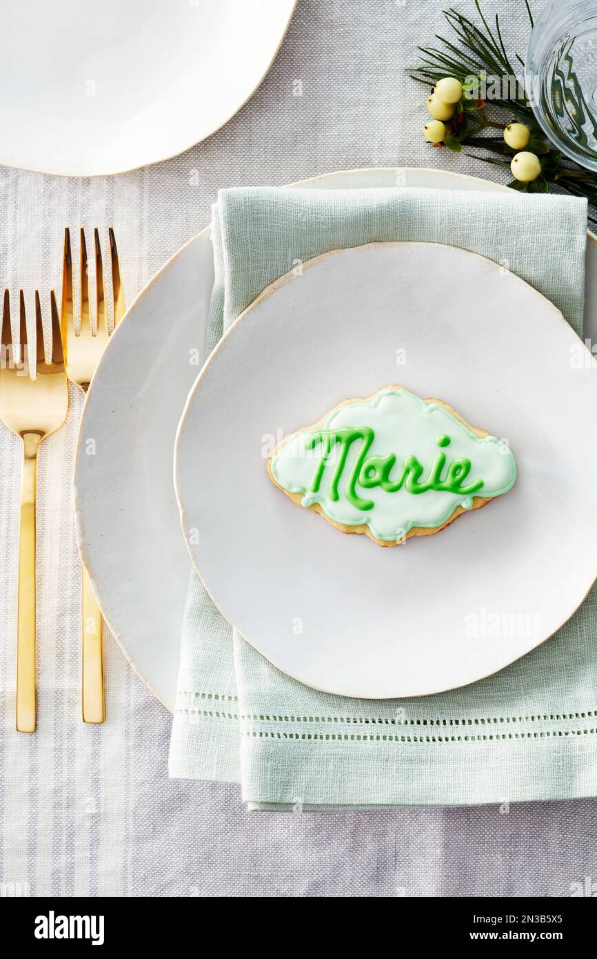 Sugar cookie place card with name in icing on a dinner plate in a ...