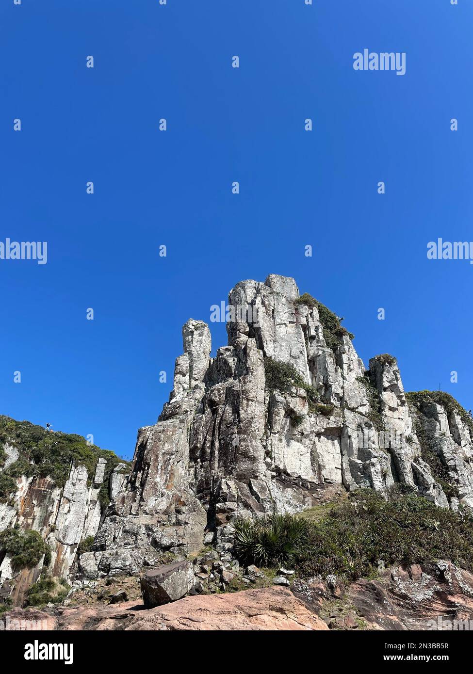 A vertical shot of a huge cliff under a clear blue sky Stock Photo - Alamy