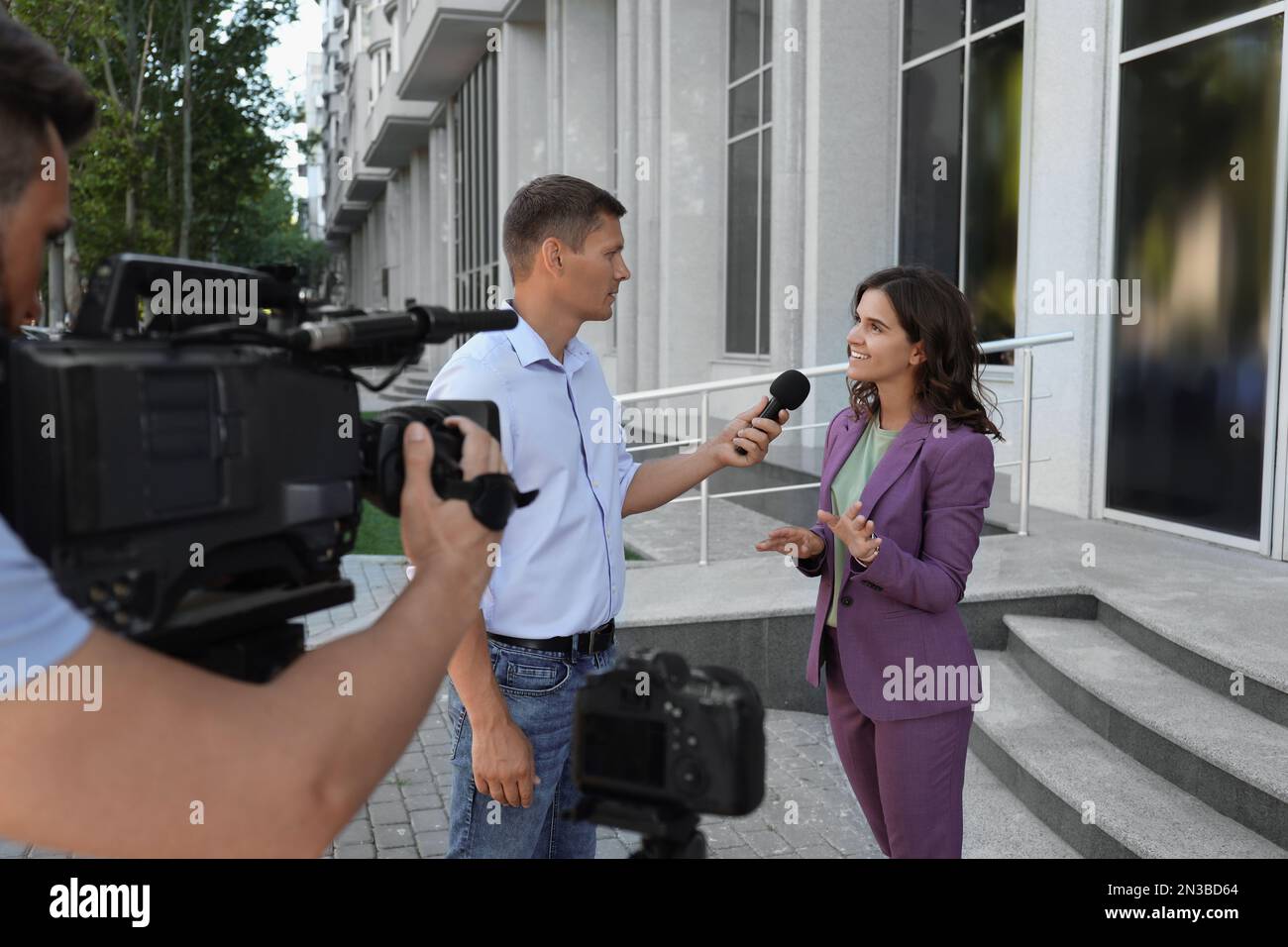 Professional journalist and operator with video camera taking interview ...