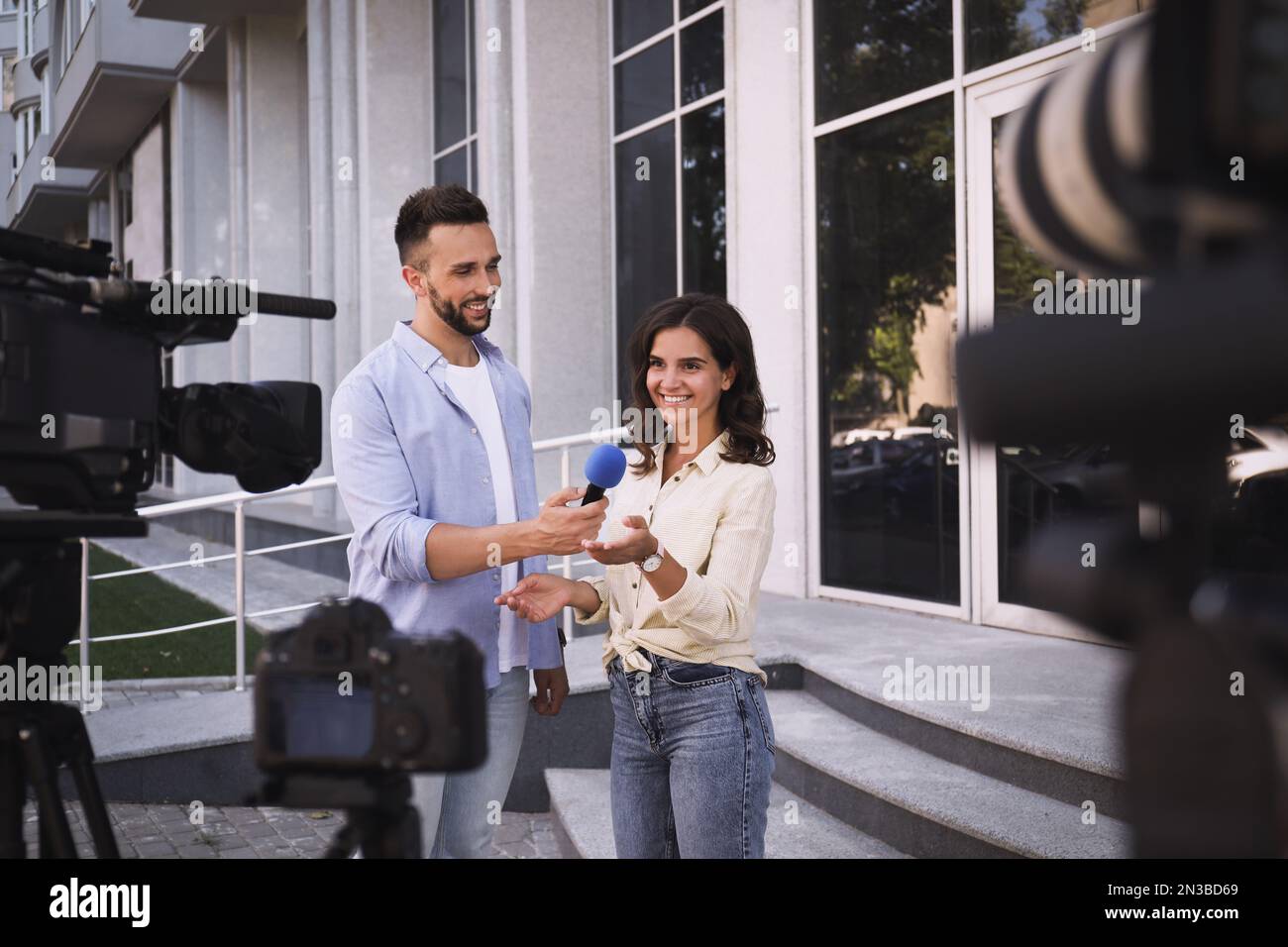 Professional journalist taking interview in front of video cameras ...