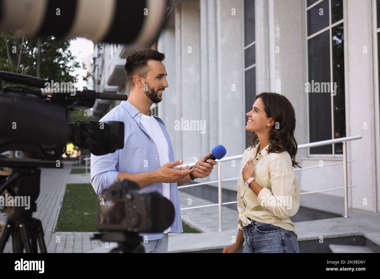 Professional journalist taking interview in front of video cameras ...