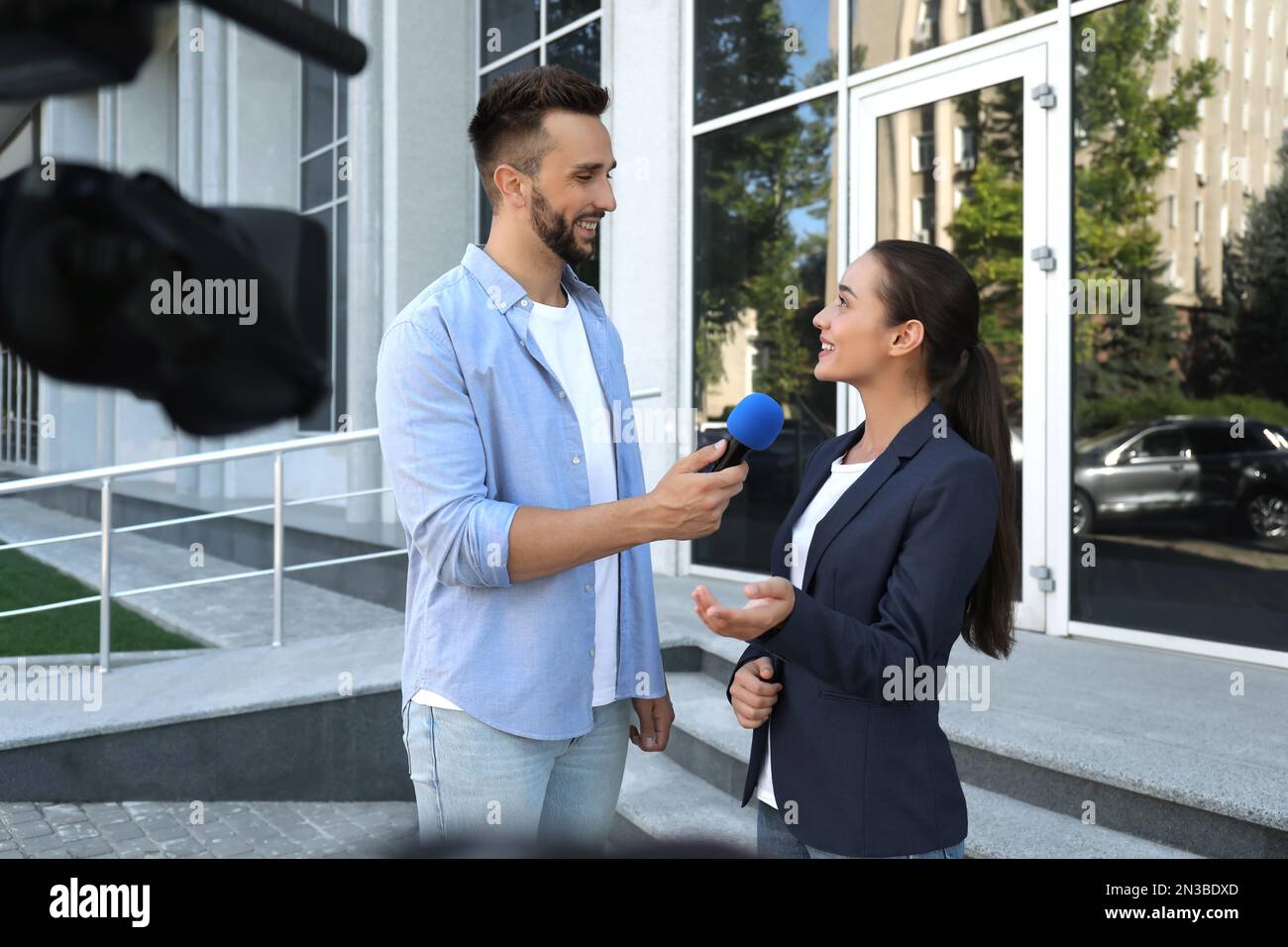 Professional journalist taking interview in front of video camera ...