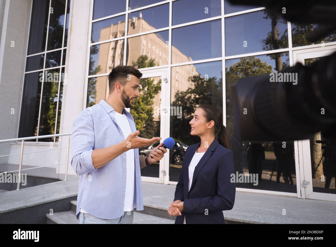 Professional journalist taking interview in front of video camera ...