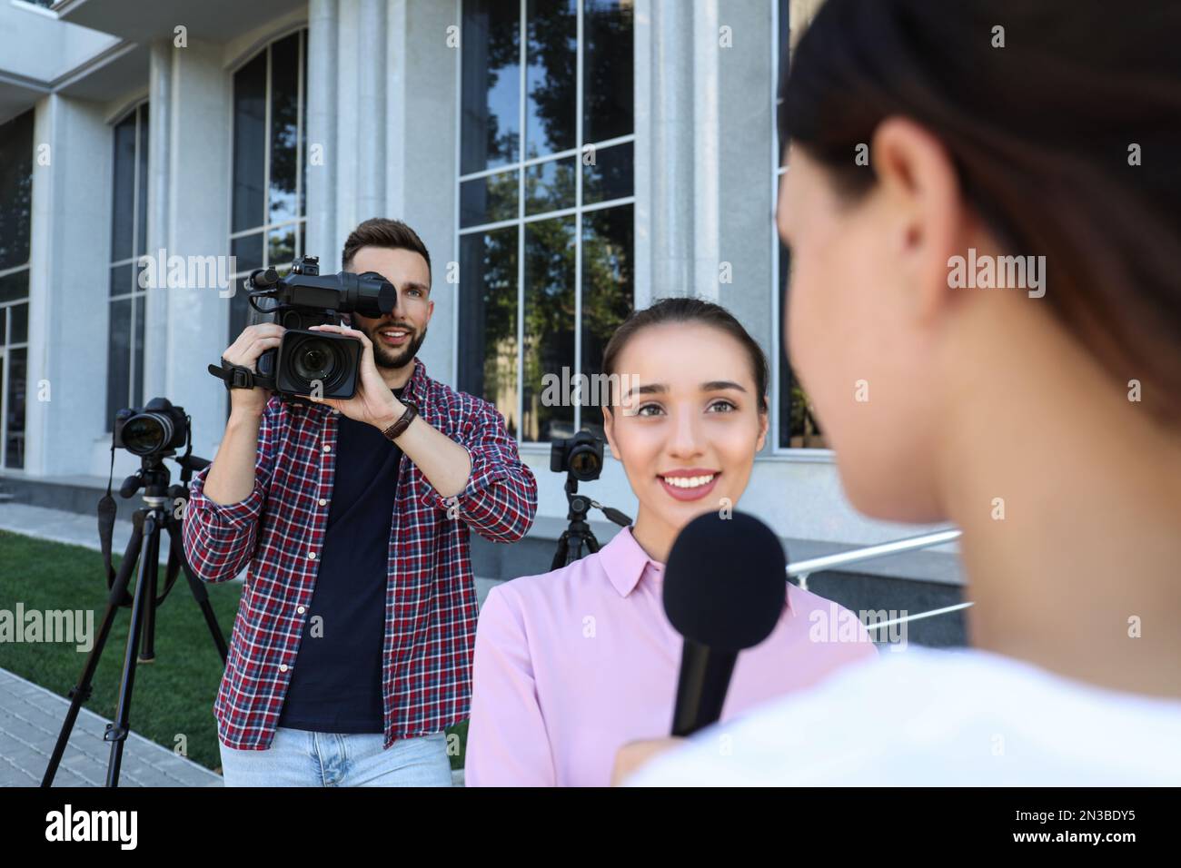 Professional journalist and operator with video camera taking interview ...