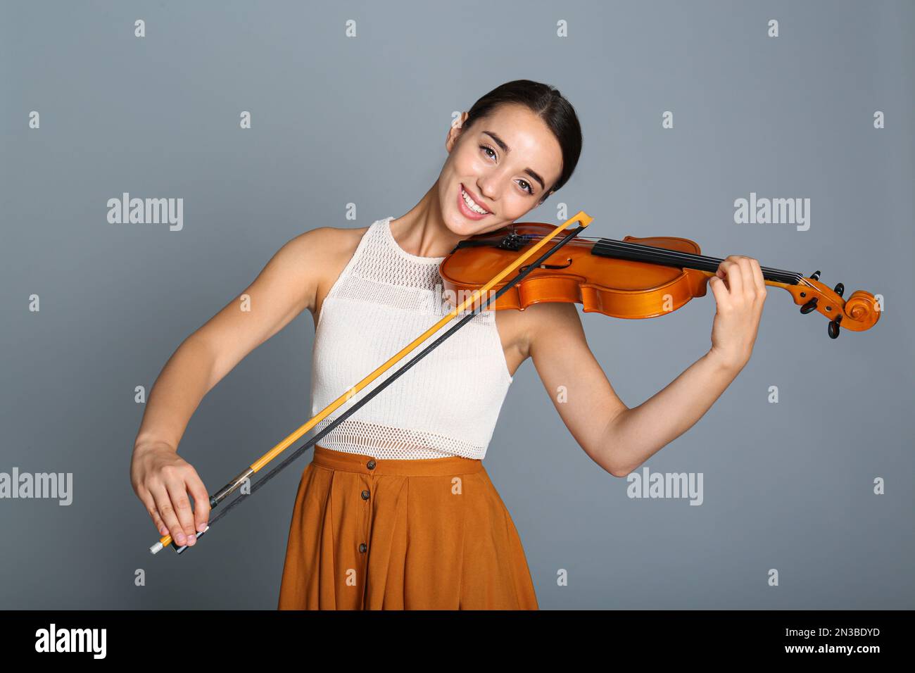 Beautiful woman playing violin on grey background Stock Photo - Alamy