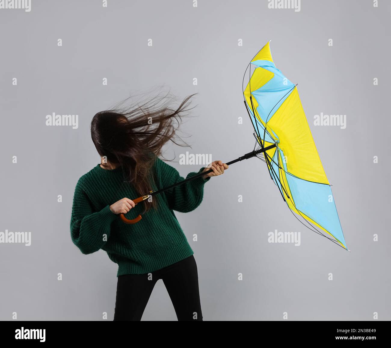 Woman with umbrella caught in gust of wind on grey background Stock ...