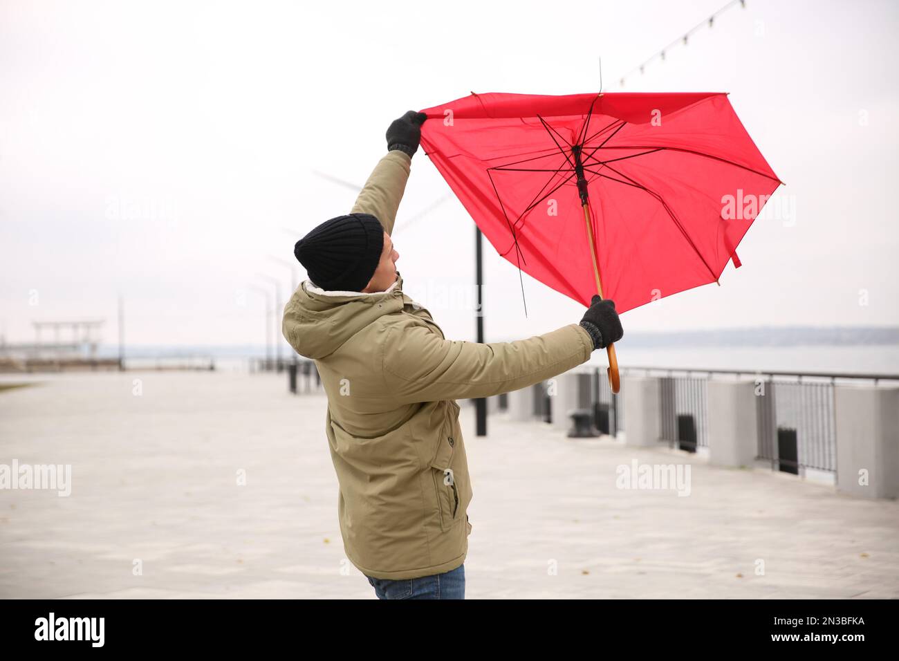 Man with red umbrella caught in gust of wind outdoors Stock Photo - Alamy
