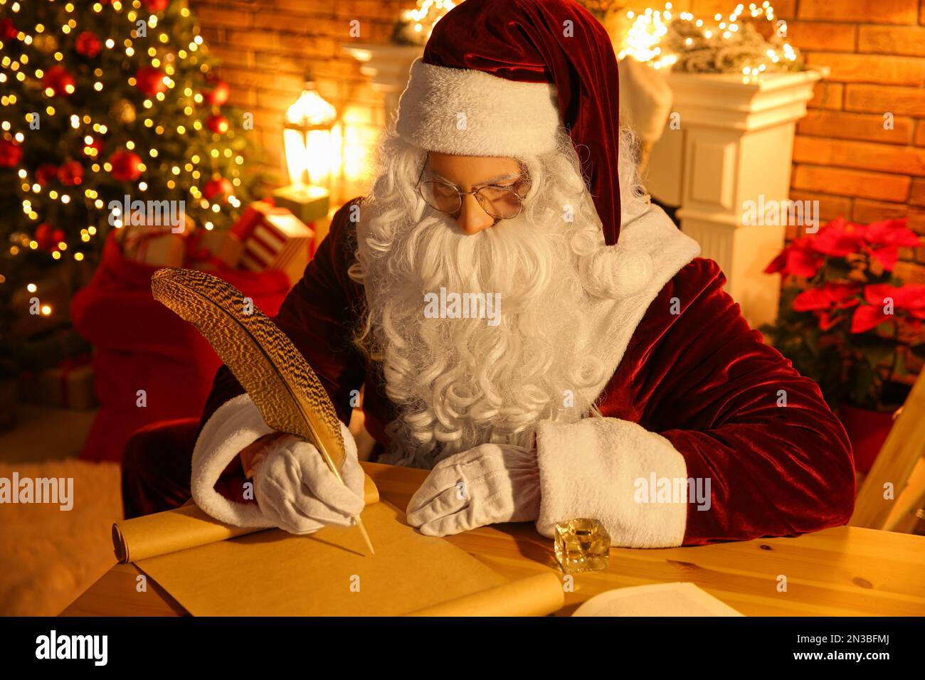 Santa Claus writing letter at table indoors Stock Photo - Alamy