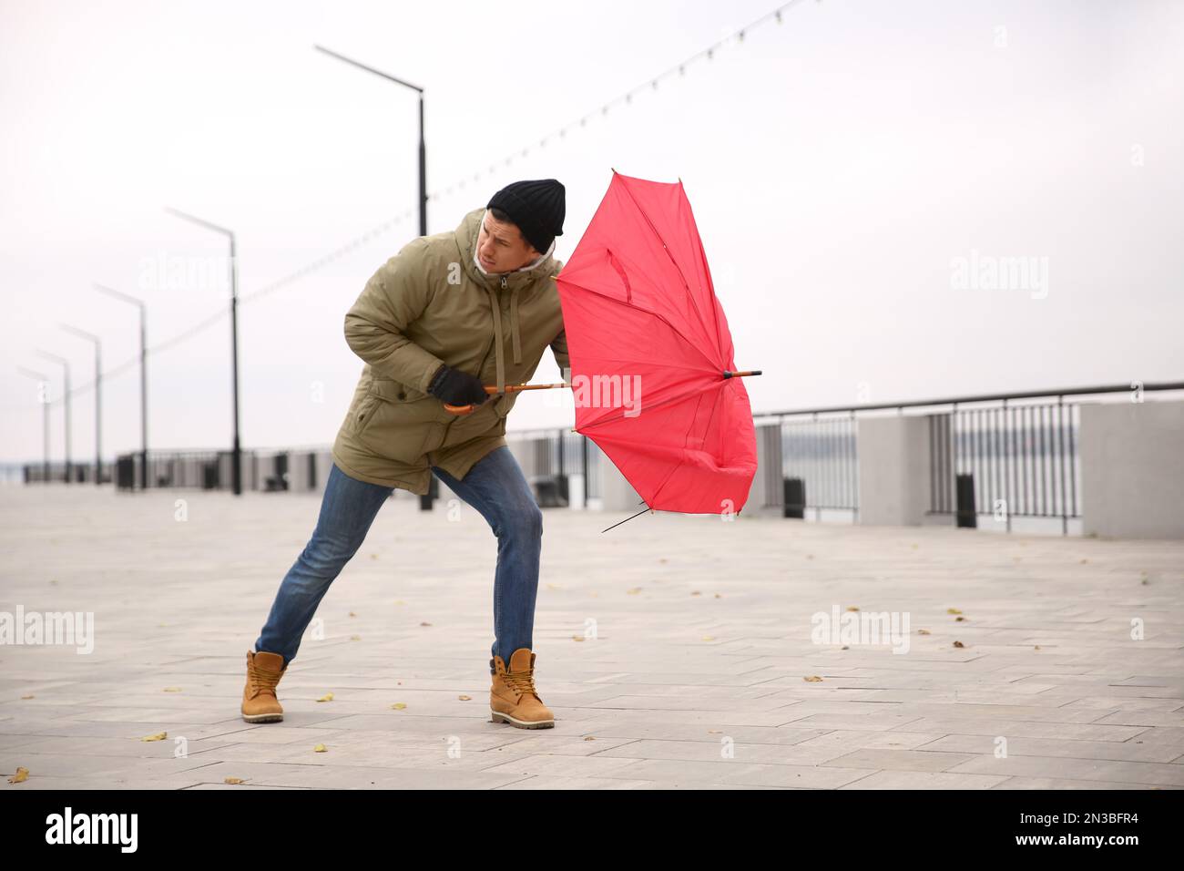 Man with red umbrella caught in gust of wind outdoors Stock Photo - Alamy
