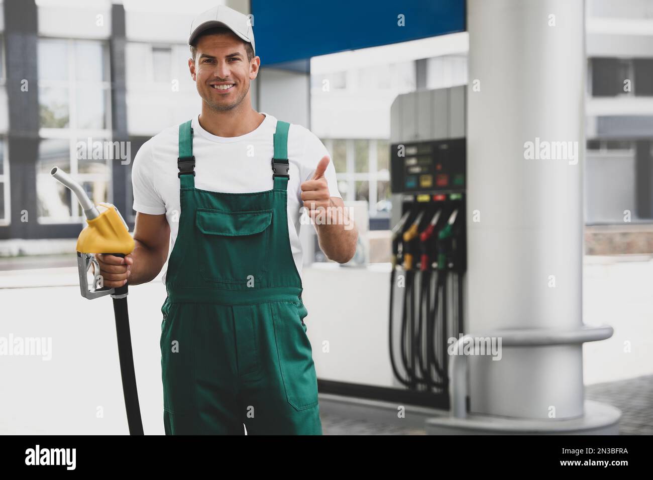 Worker with fuel pump nozzle at modern gas station Stock Photo - Alamy