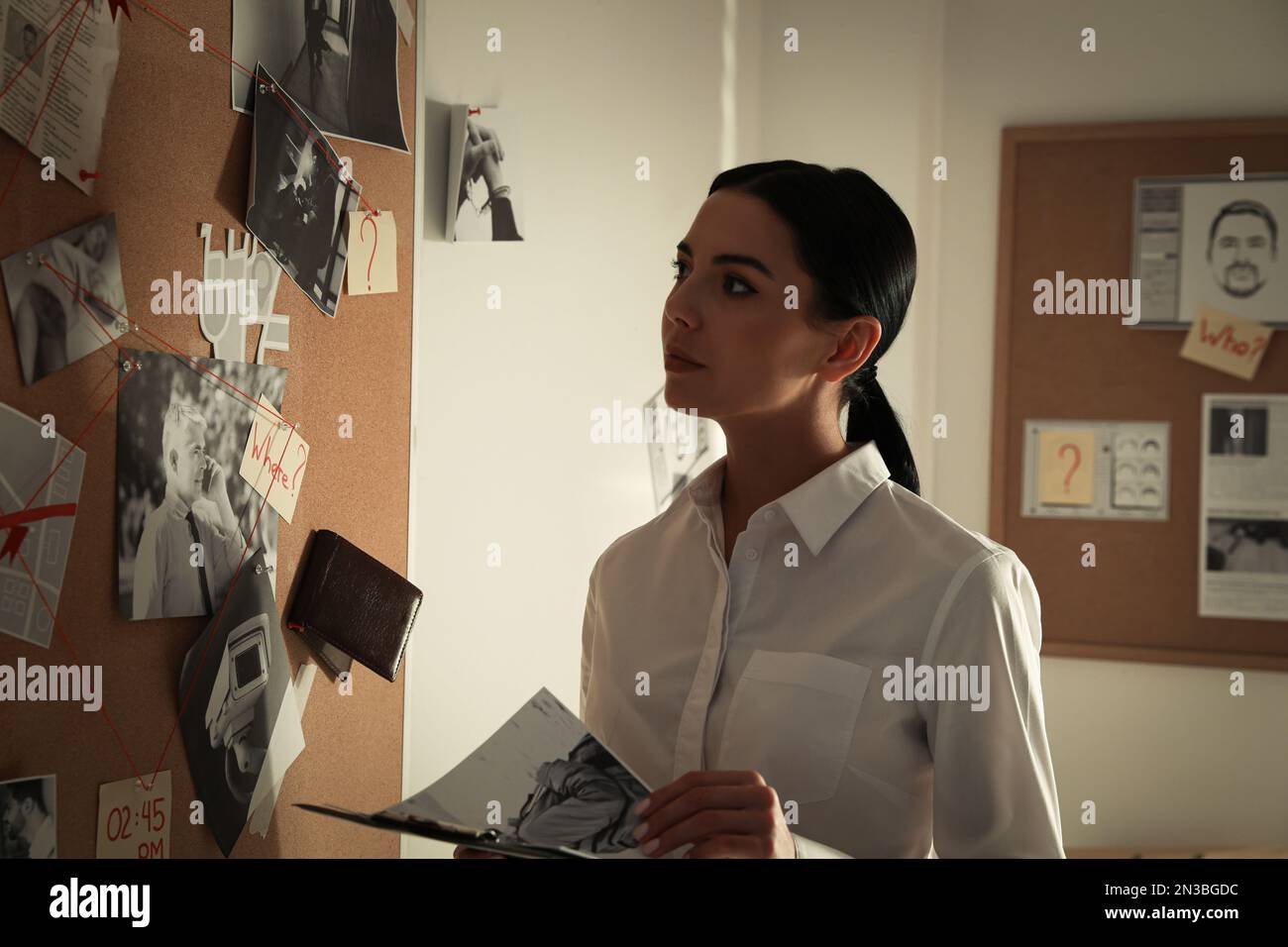 Detective looking at evidence board in office Stock Photo - Alamy