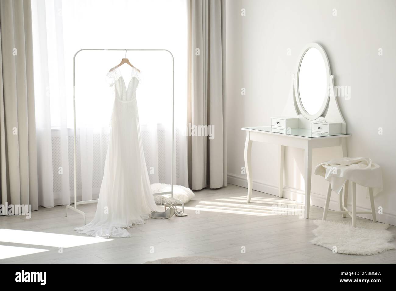 Beautiful wedding dress hanging on clothing rack in room Stock Photo ...