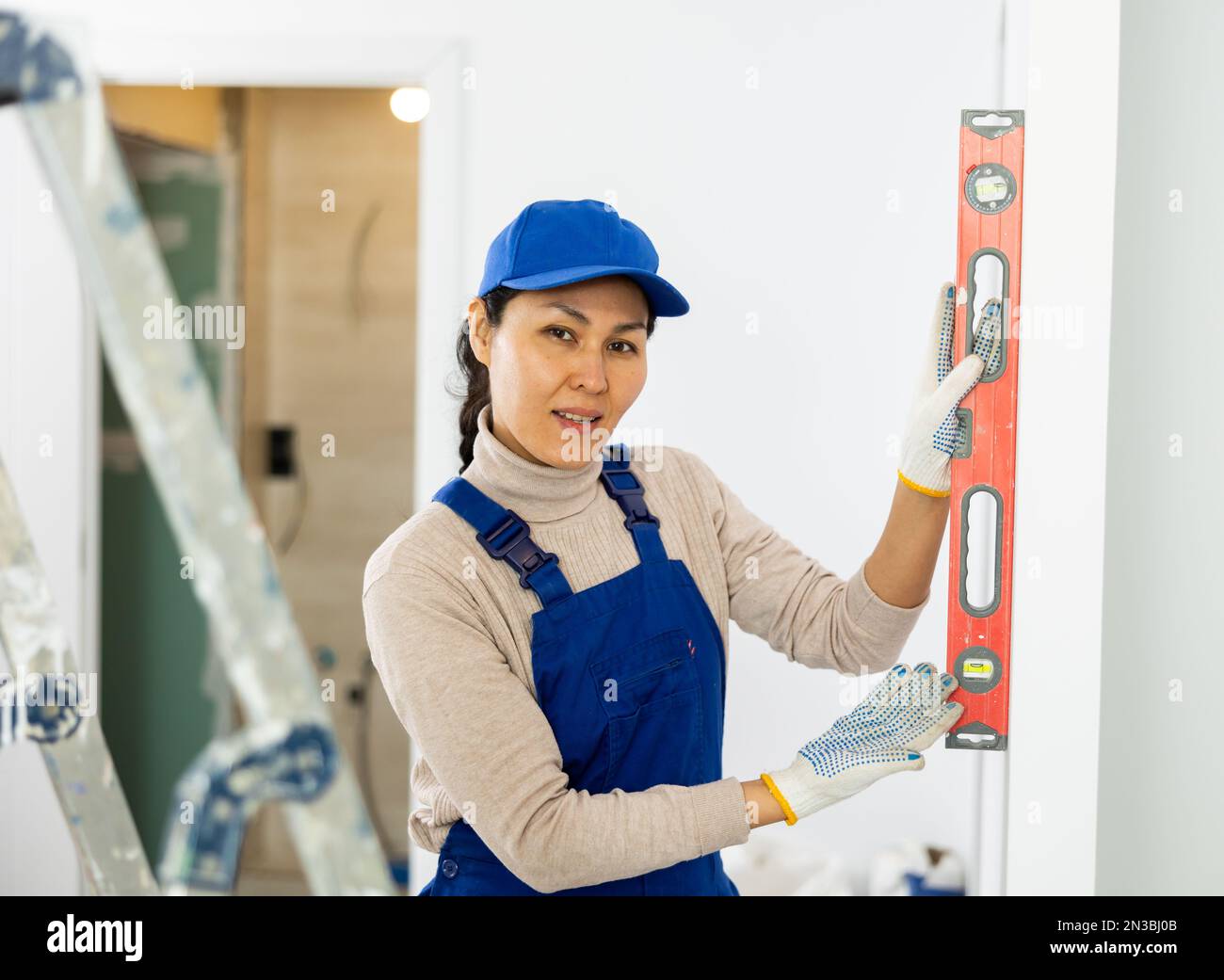 Woman builder using building level measures the vertical of wall Stock ...