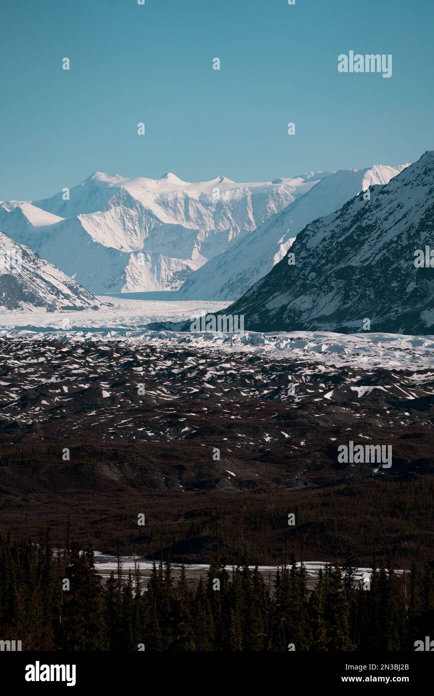 The Matanuska Glacier flows with the towering snow covered peaks of the ...