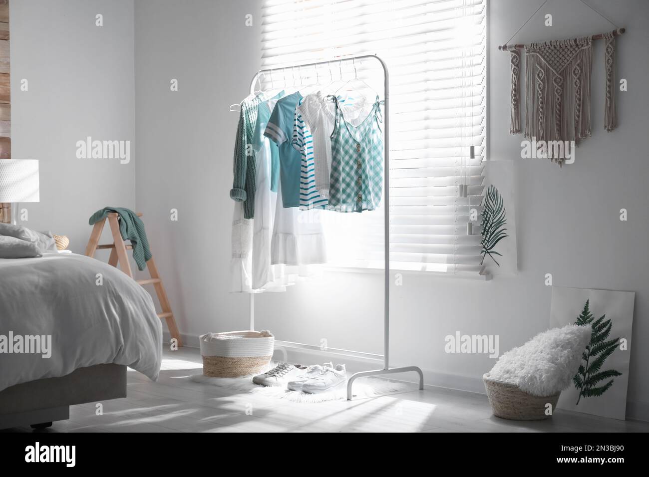 Stylish bedroom interior with clothing rack and large window Stock ...