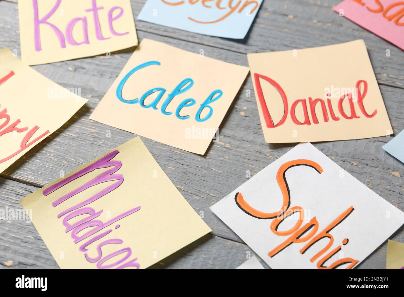 Colorful paper sheets with written different baby names on grey wooden ...