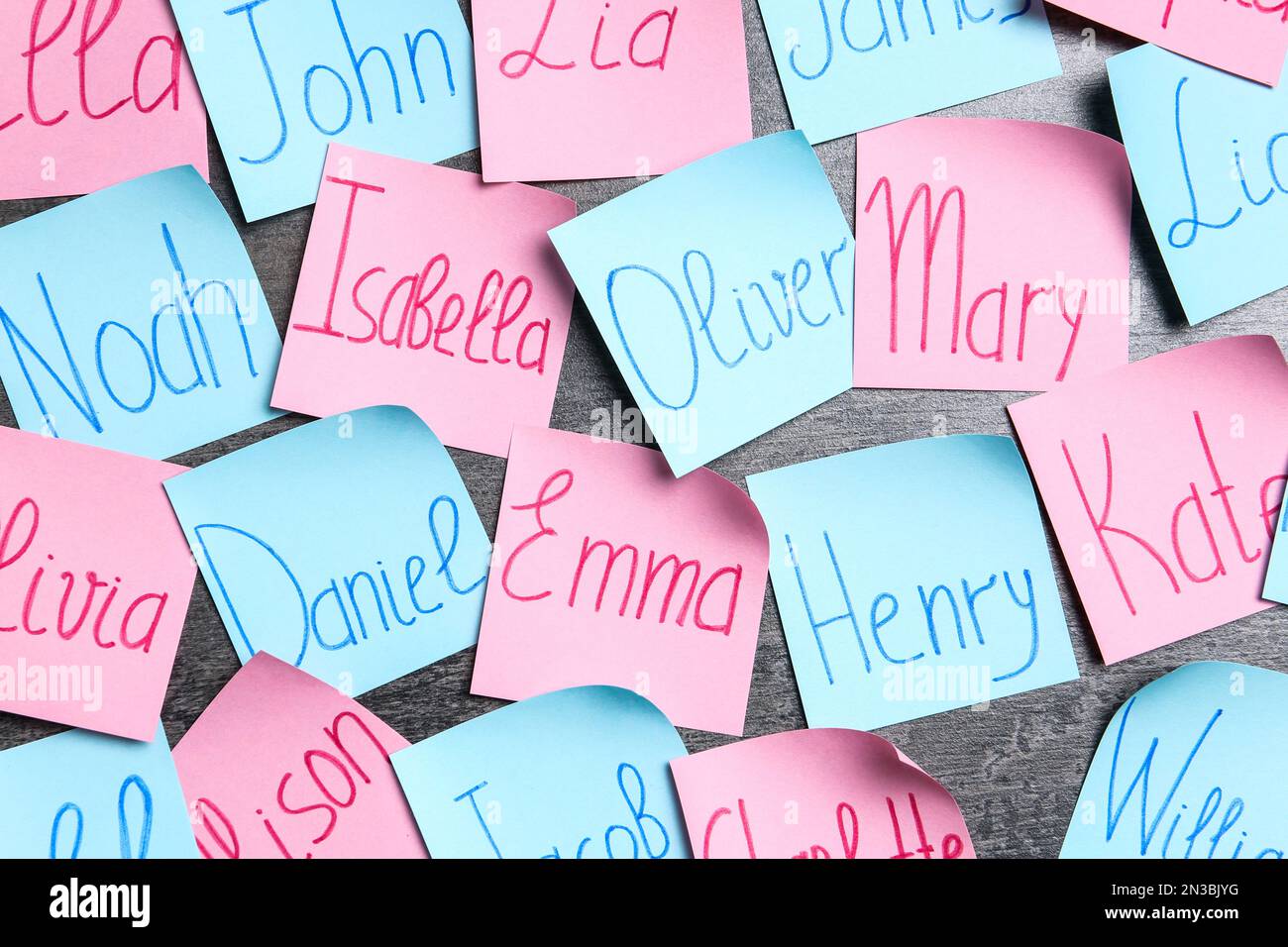 Paper notes with different baby names on grey background, flat lay ...