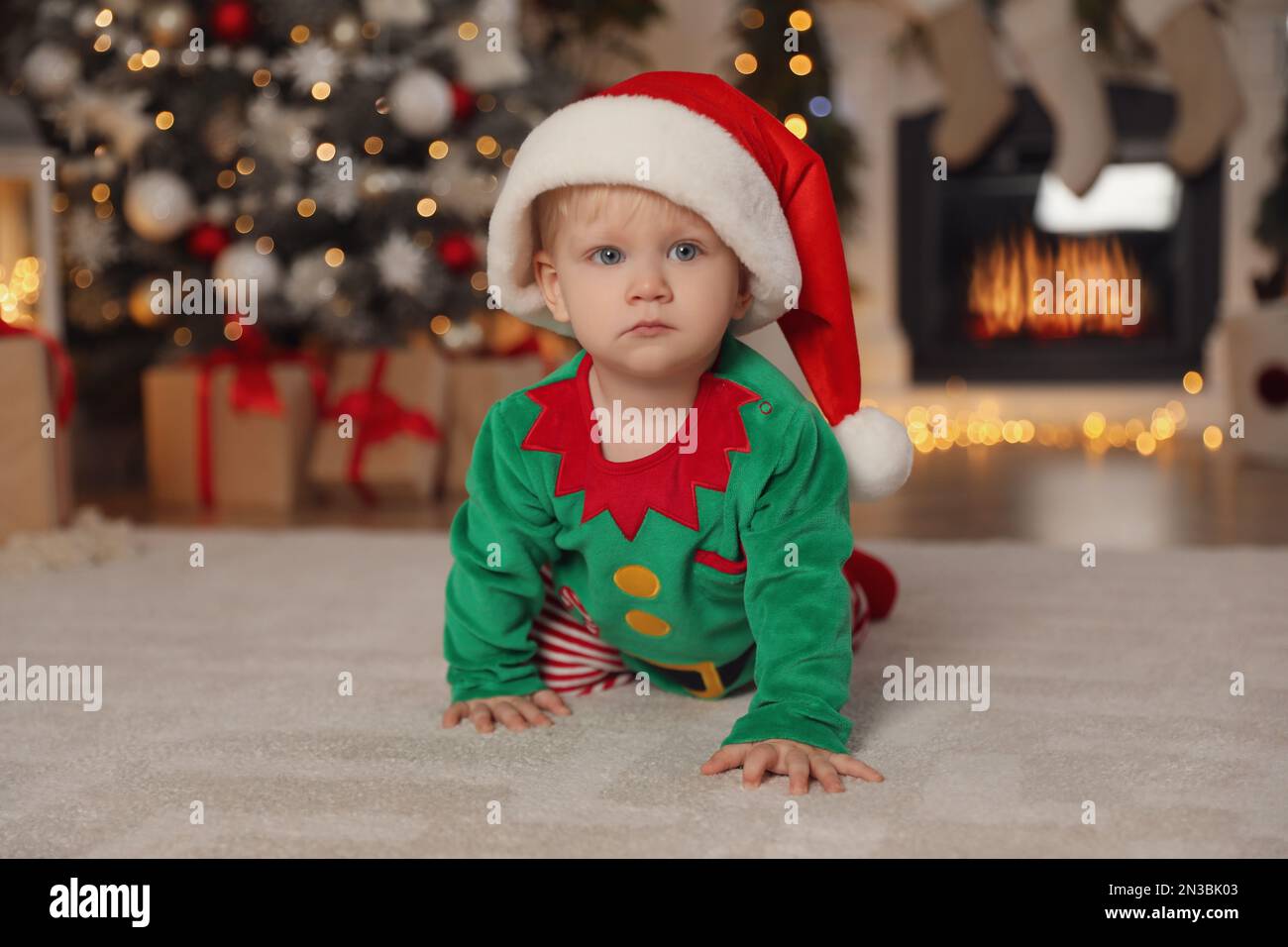 Cute baby wearing Santa's elf clothes in room with Christmas ...