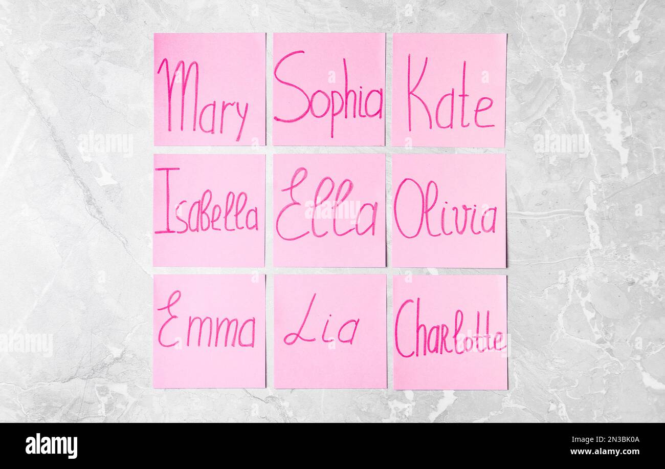 Paper notes with different baby names on grey marble table, flat lay ...