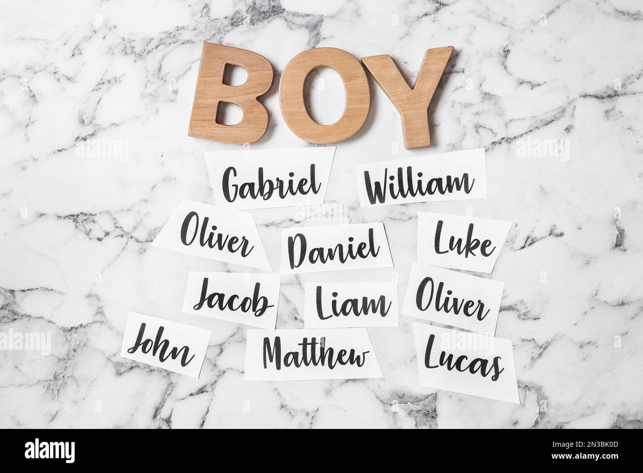 Paper sheets with different baby names and wooden letters on white ...