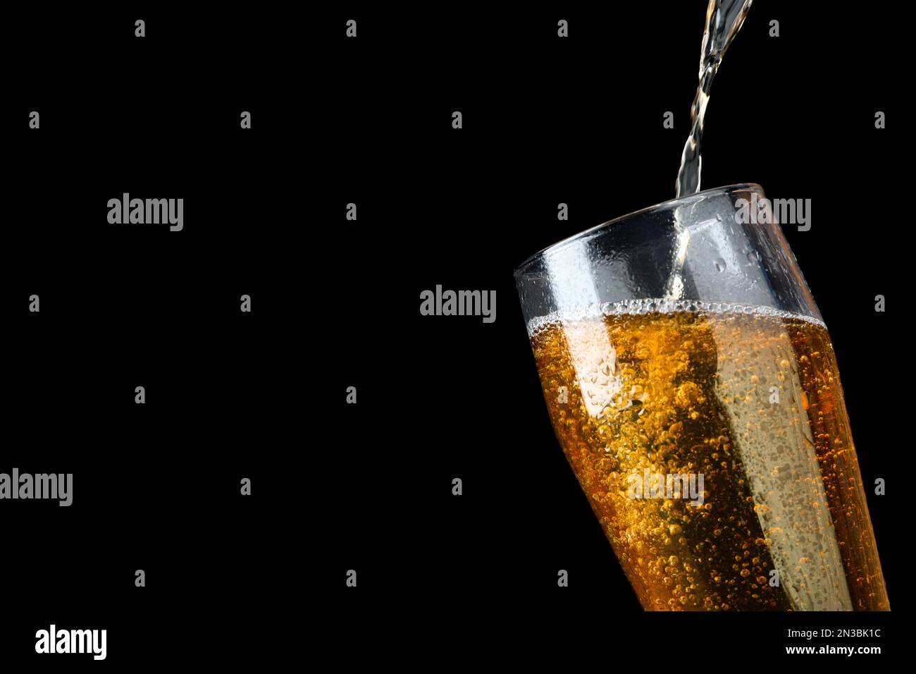 Pouring cold tasty beer into glass on black background, closeup. Space ...