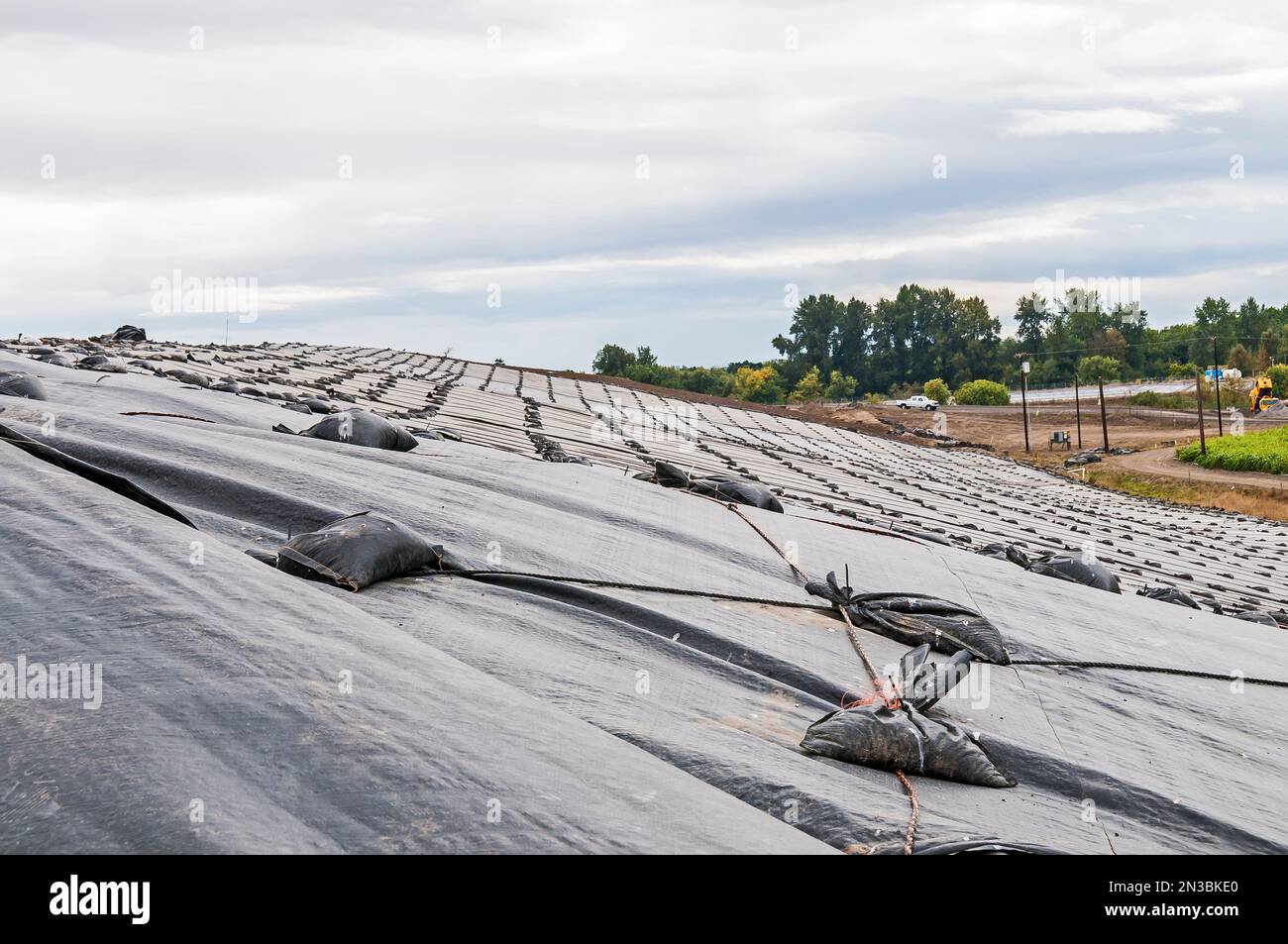 Weighted plastic sheeting covers a hillside in an active landfill ...