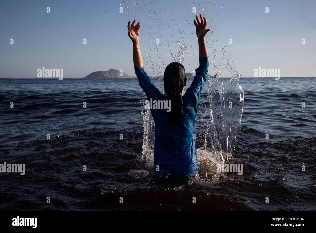 A devotee of the sea goddess Yemanja prays to her in the waters of ...