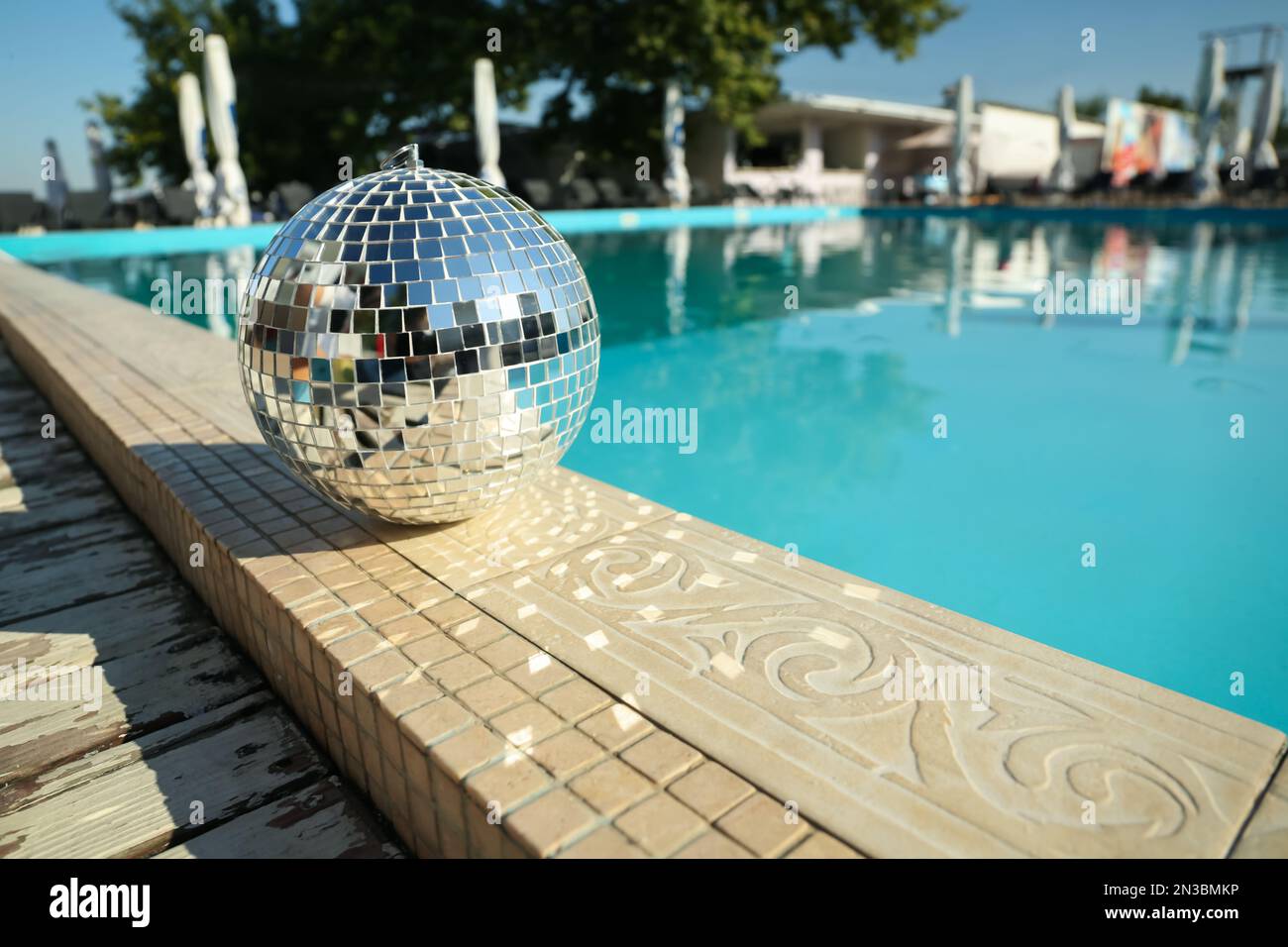 Shiny disco ball on edge of swimming pool. Party decor Stock Photo - Alamy